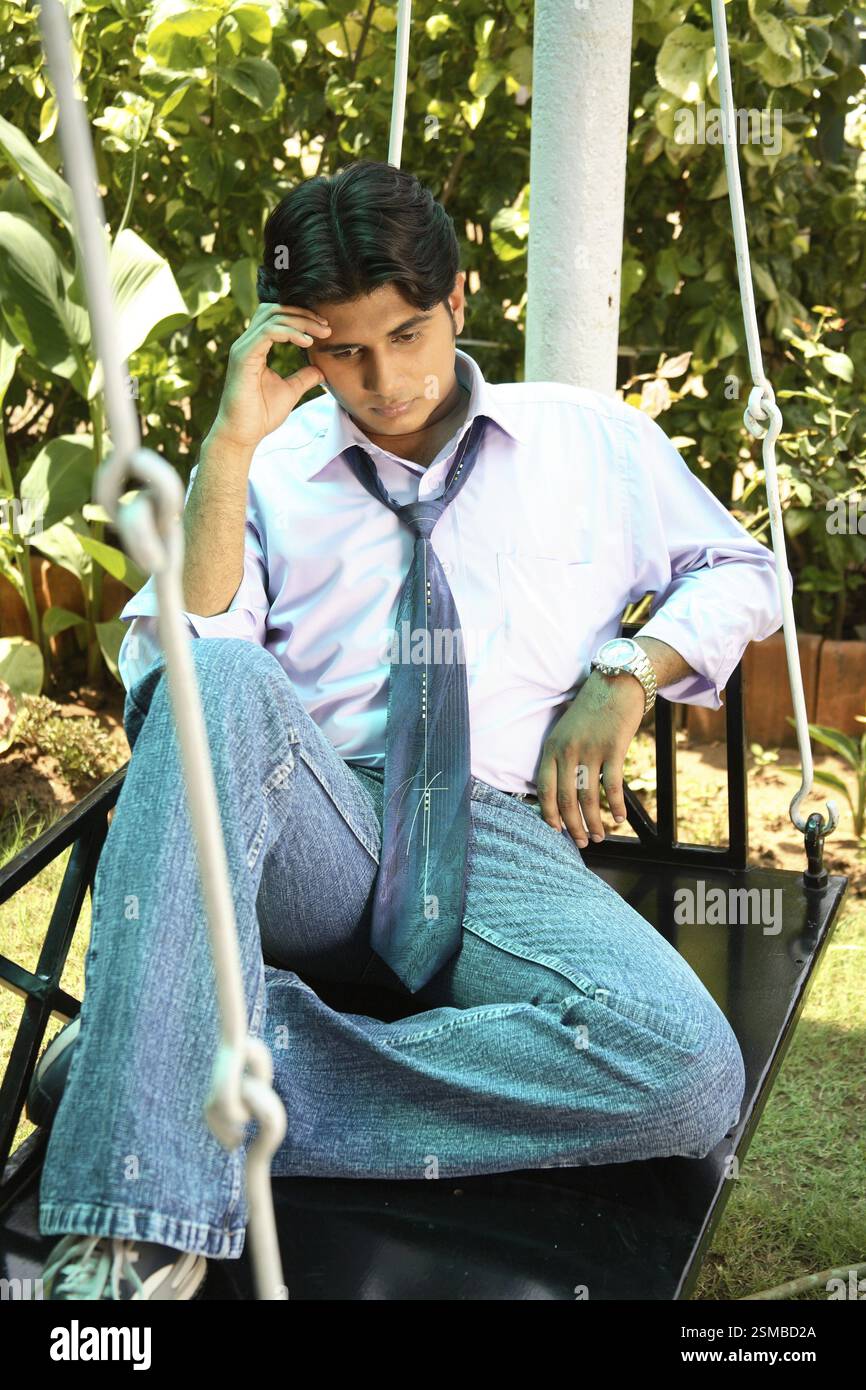 Young man sitting swing and thinking touching his head with hand MR ...