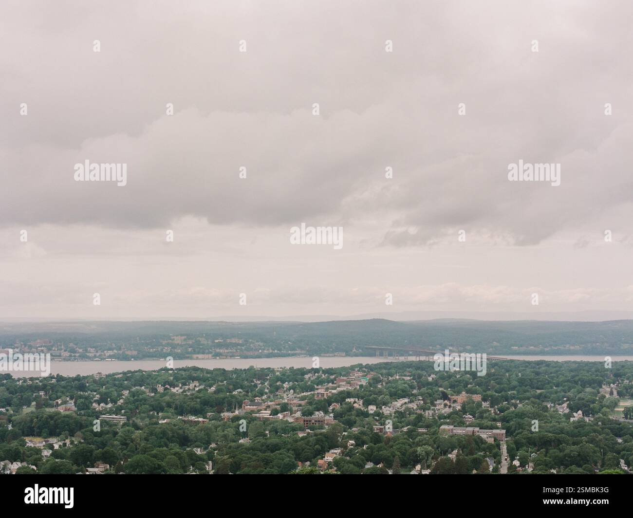 A panoramic landscape shows houses nestled among trees, with a river ...