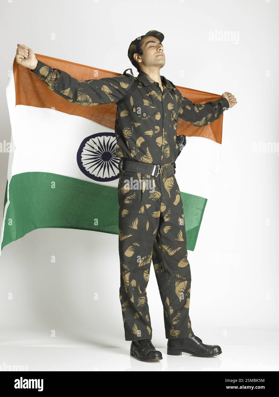Indian army soldier standing holding flag of India on his backside MR ...