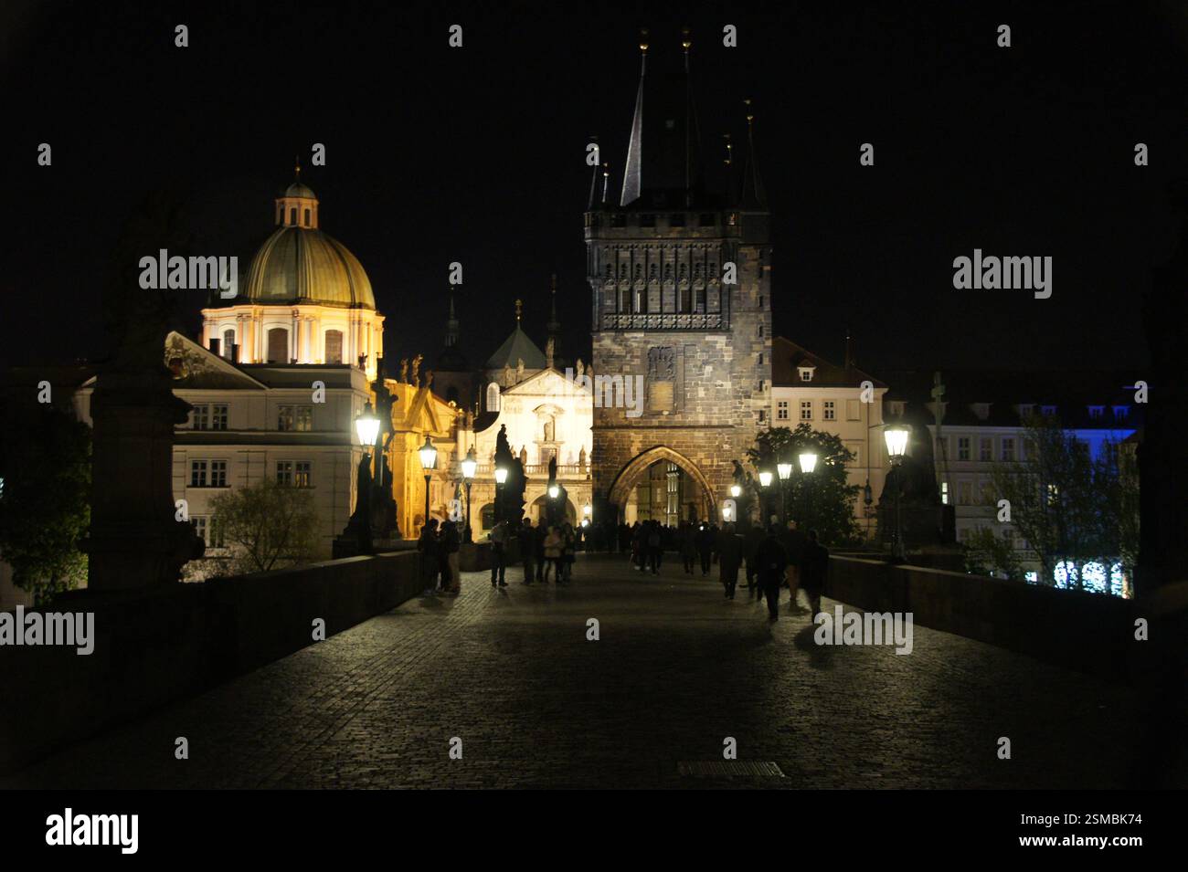 Charles Bridge, a night view of the bridge with illuminated buildings and pedestrians. Iconic ...