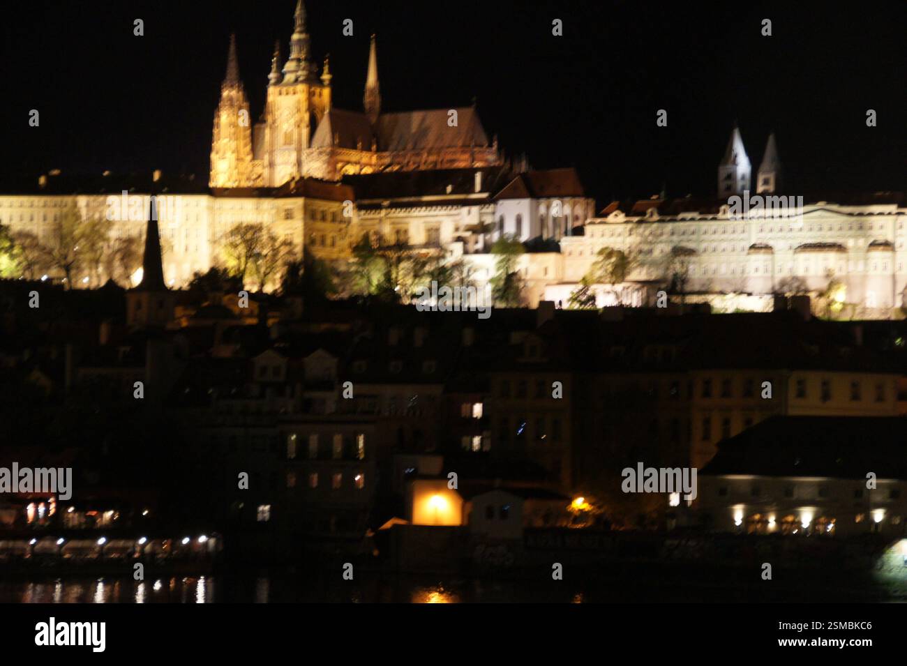 Prague Castle, a sprawling complex of buildings illuminated at night ...