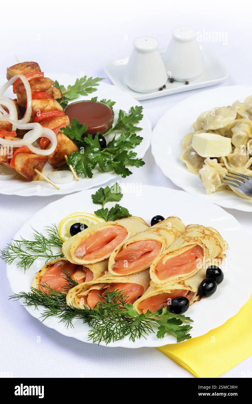 Food with meat, salmon rolls and dumplings. Table with white background ...