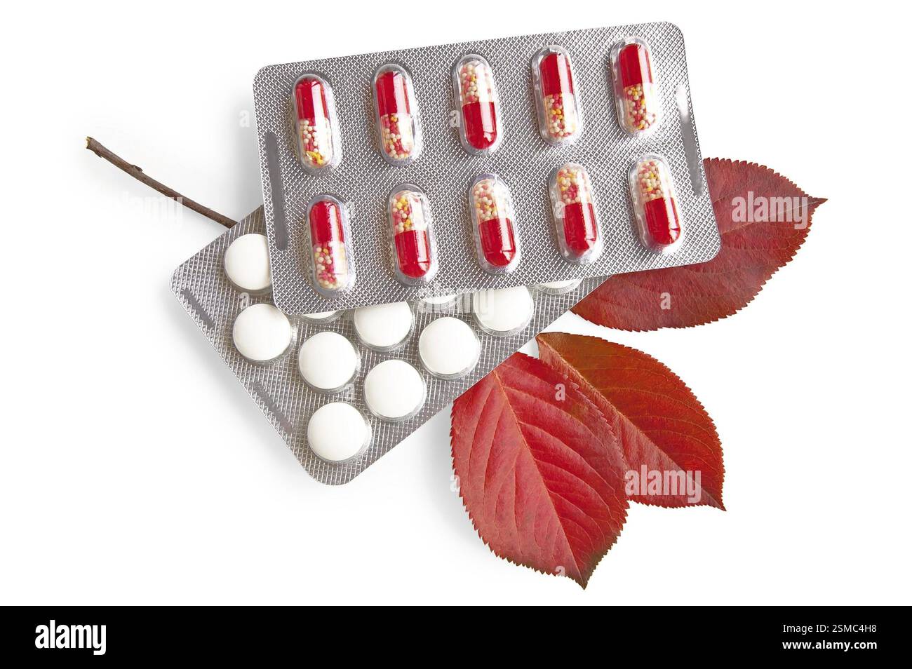White round pill, red capsules in packs, with a sprig of red leaves ...