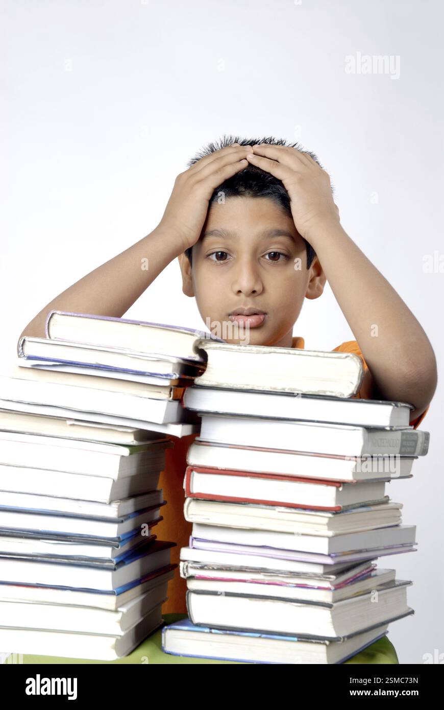 Boy in tension holding head standing with stack of books MR#152 Stock ...