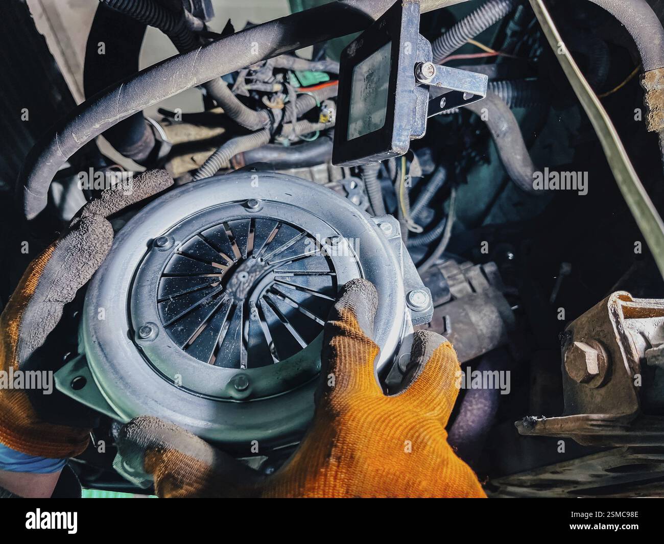 Mechanic aligns a clutch disk on a car engine with orange gloves Stock ...
