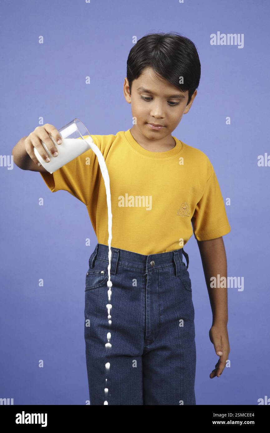 Ten year old boy holing glass of milk and pouring it on floor MR#703V Stock Photo - Alamy