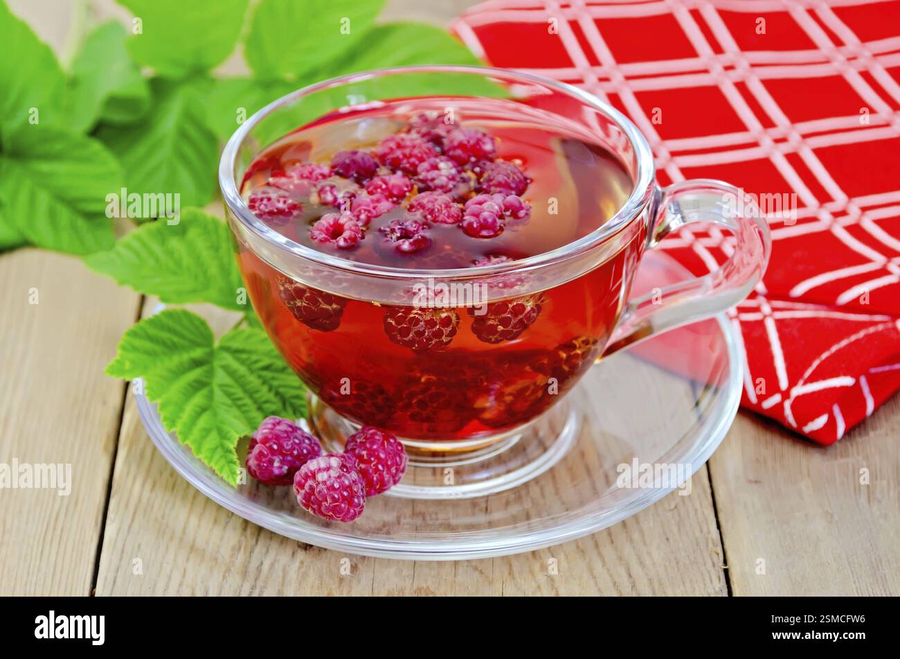 Tea with raspberries in a glass bowl, green leaves of raspberry, red ...