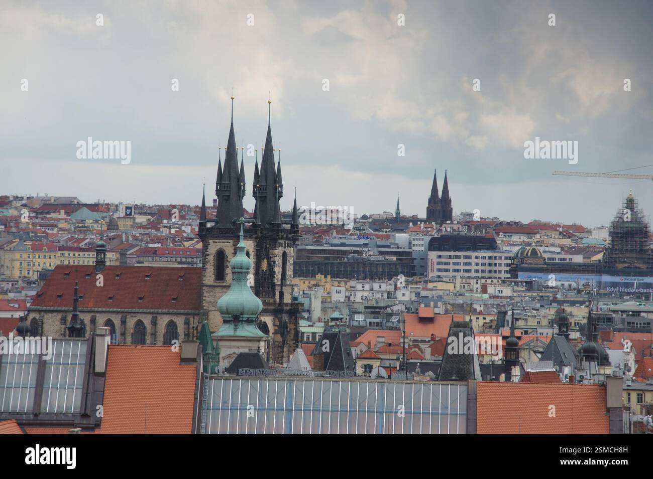 Prague skyline. Red rooftops and Gothic spires dominate the cityscape. Cloudy sky adds a ...