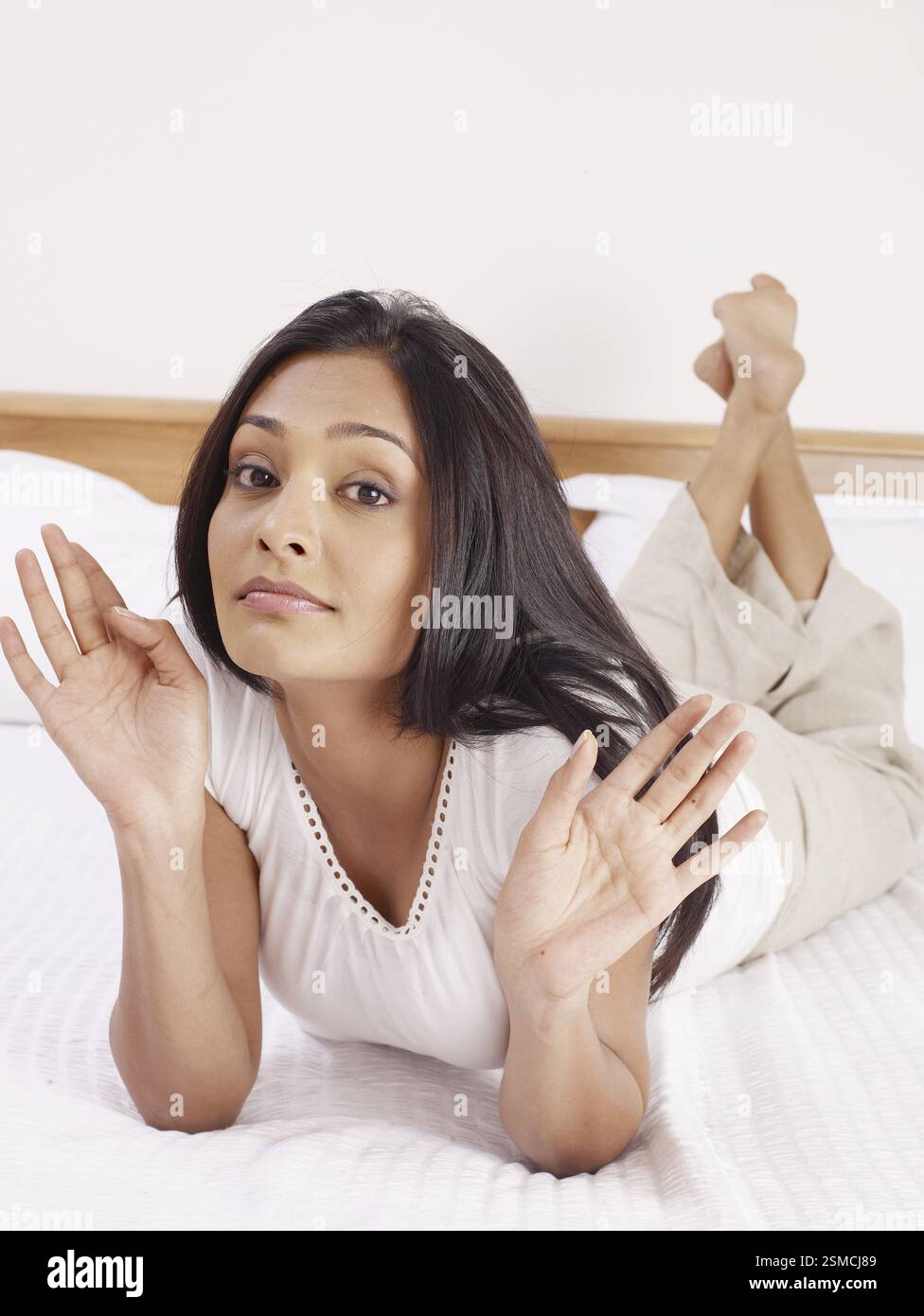Young lady expressing with hands laying on bed MR#702U Stock Photo - Alamy