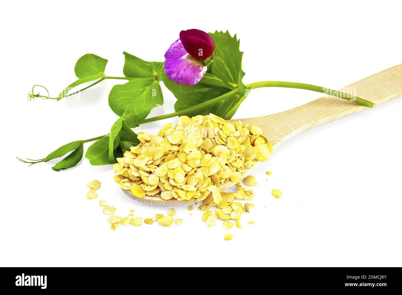 Pea flakes in a spoon and a table with a flower and green leaves ...