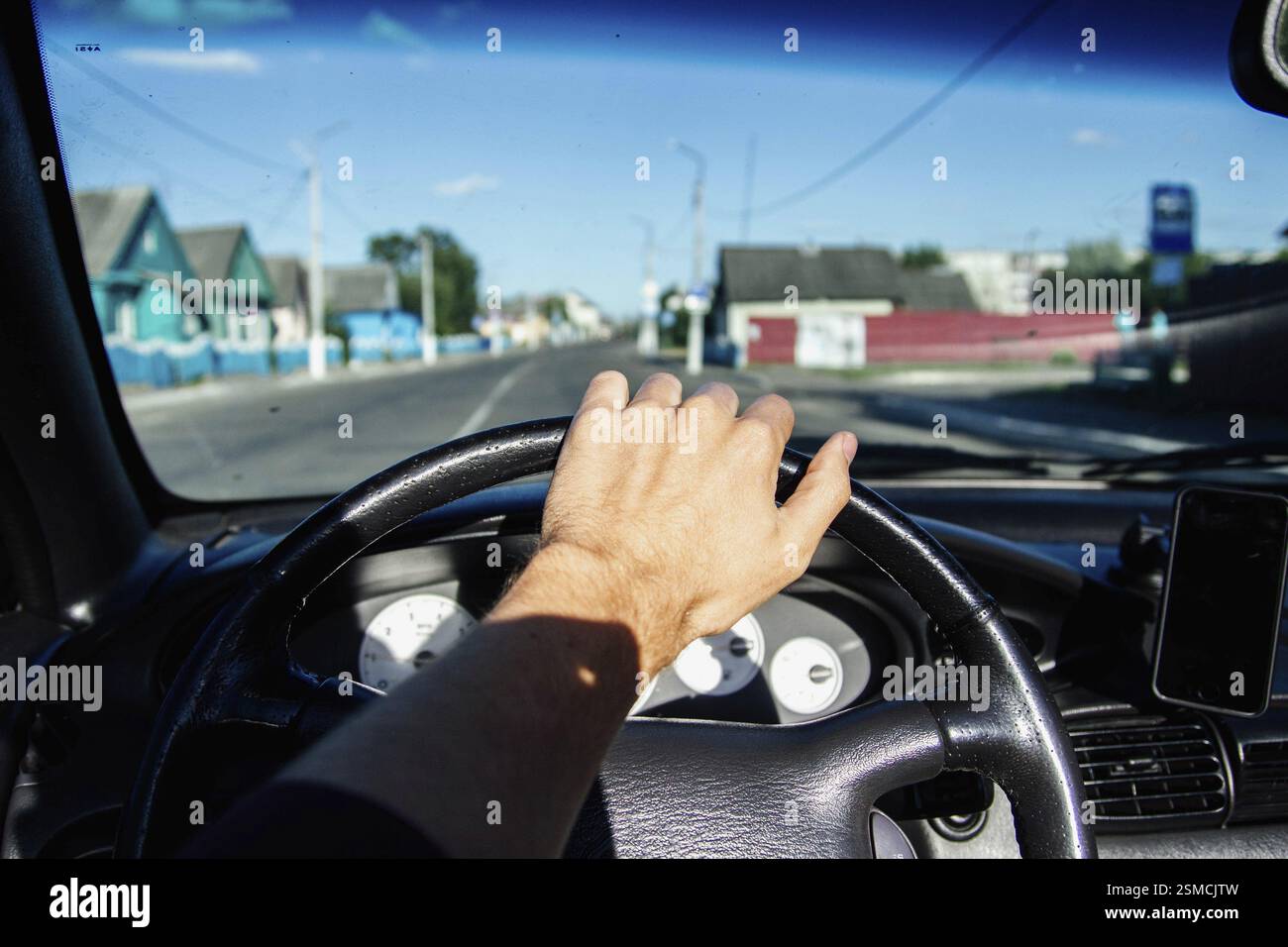 Driving view with hand on the steering wheel, sunny weather and ...