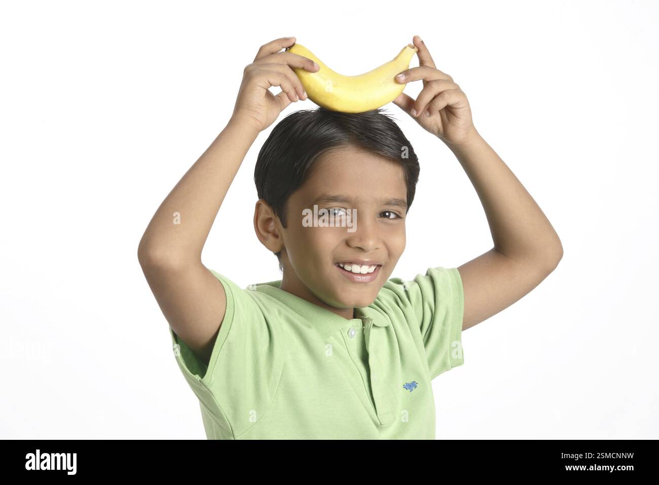 Ten year old boy kept yellow banana on head holding with both hand ...