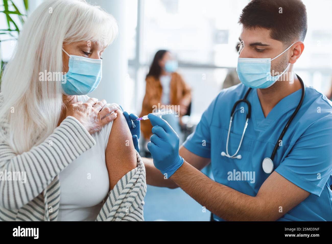 Mature Woman Receiving Vaccine Injection Sitting With Doctor Indoor ...