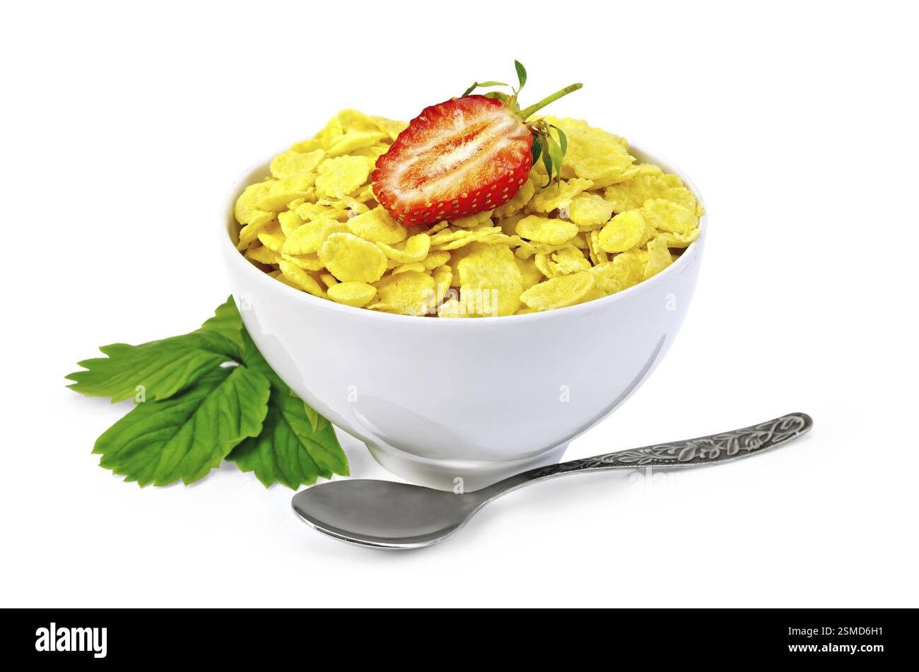 Cornflakes in a white bowl, berries and strawberry leaves, spoon ...