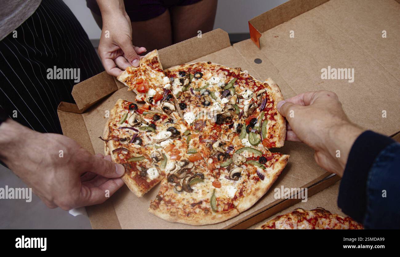 Hands grabbing a slice of veggie pizza from a takeout box Stock Photo ...