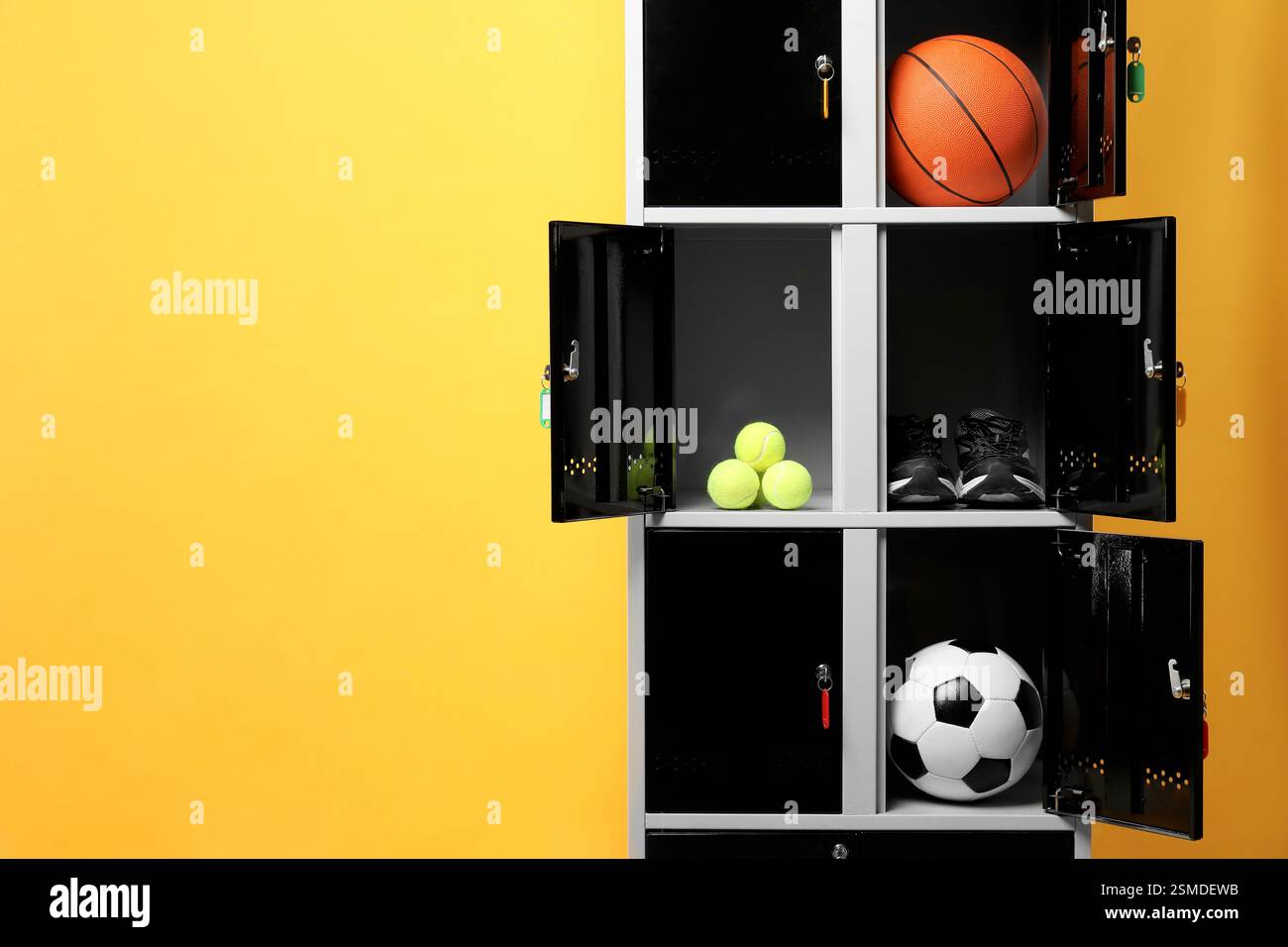Open lockers with sport equipment on orange background, space for text ...