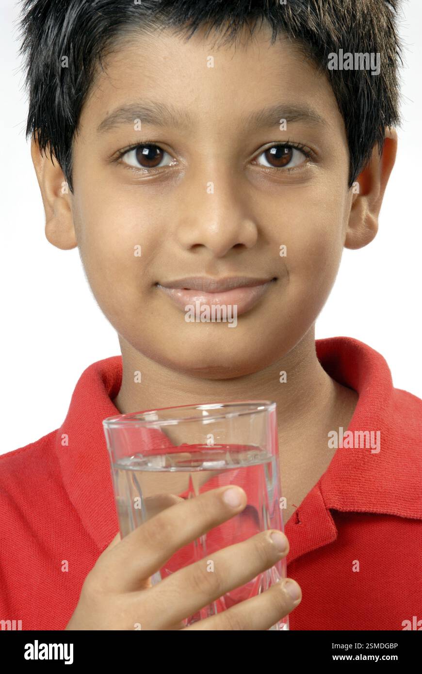 South Asian Indian boy holding glass full of mineral water to drink MR ...