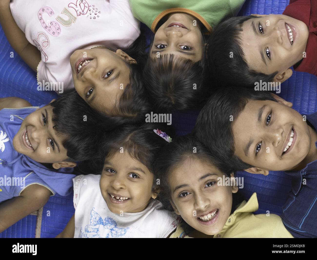 South Asian Indian boys and girls lay down on floor in nursery school ...