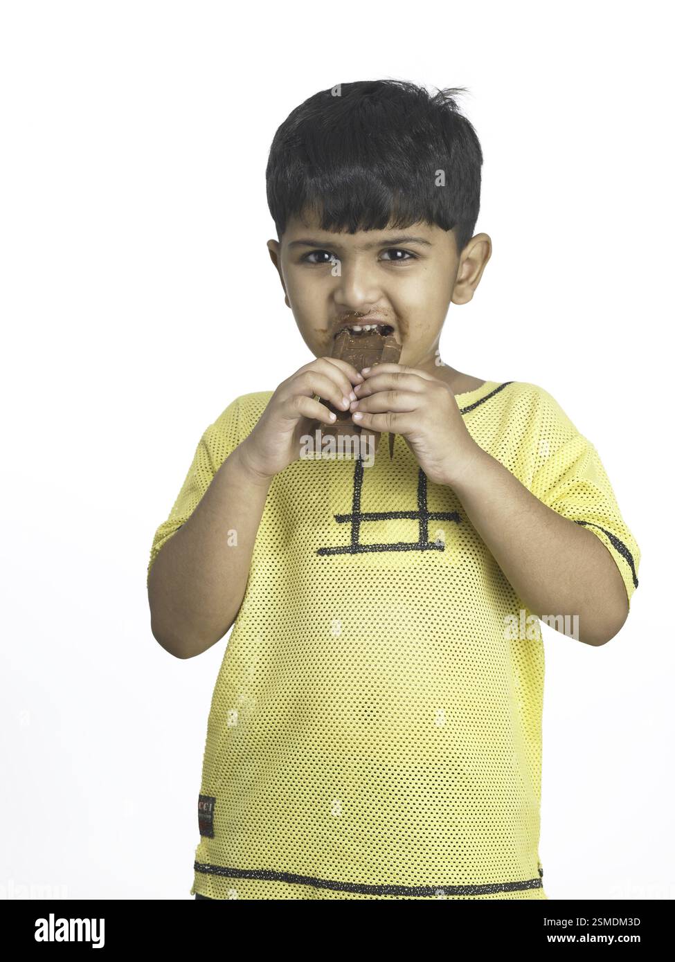 South Asian Indian boy eating chocolate in nursery school MR Stock ...