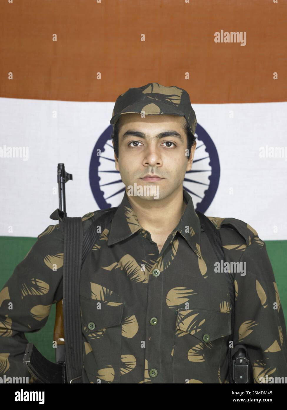 Indian army soldier standing with gun in front of flag of India in ...