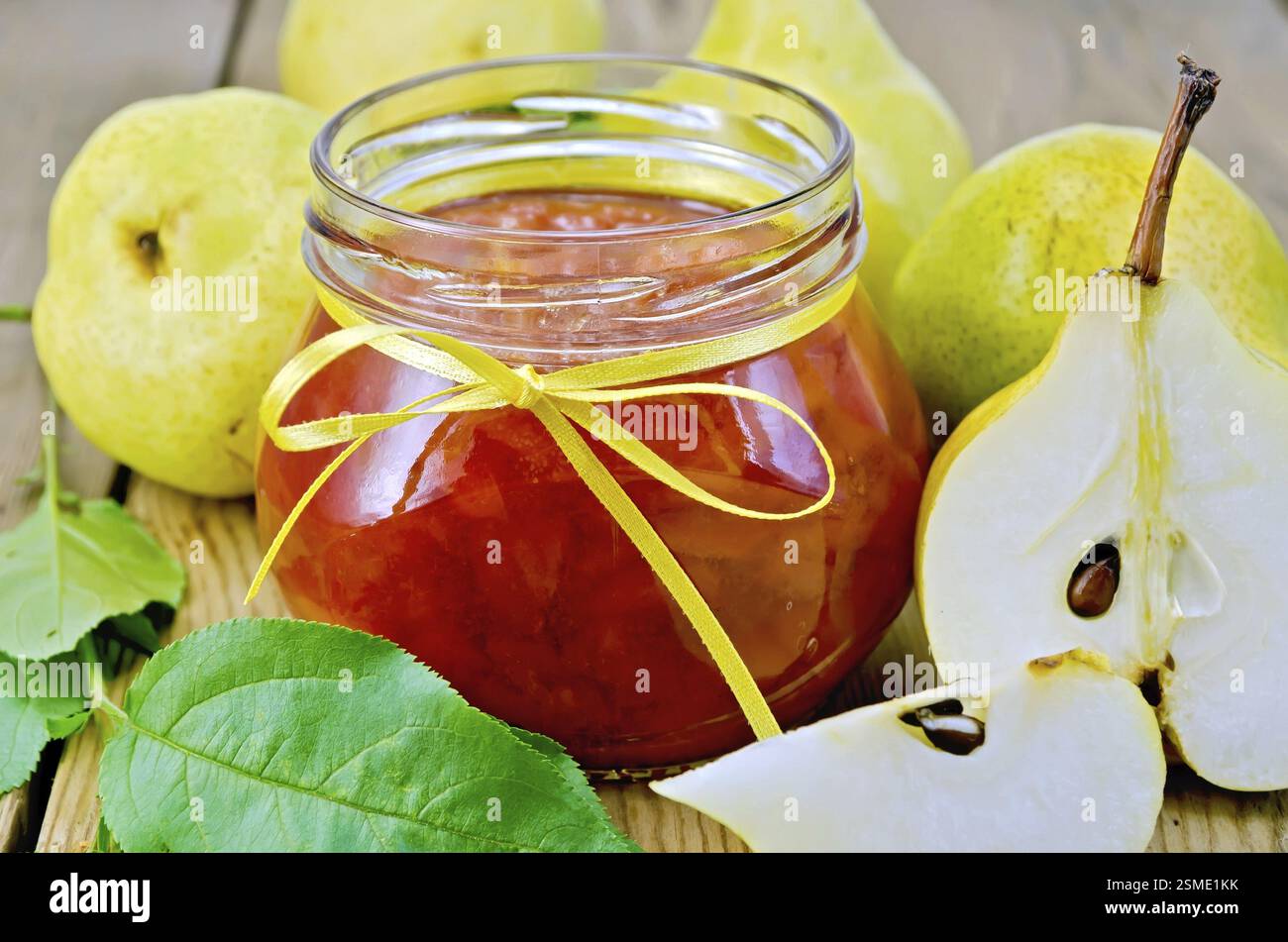 Pear jam in a glass jar, fresh pears, twigs with leaves on the ...