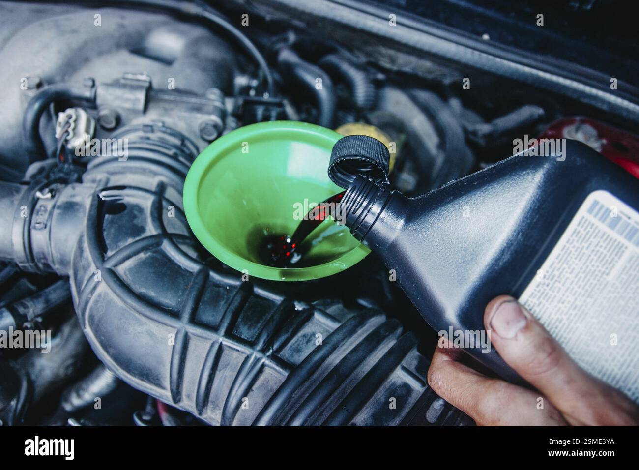 Oil poured into a green funnel under a car hood Stock Photo - Alamy