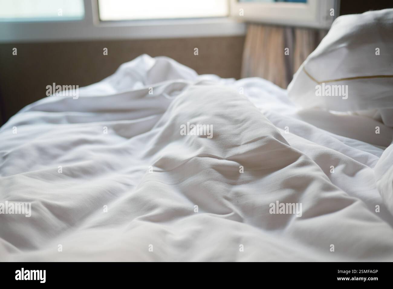 Soft, crumpled sheets on a cozy bed in a sunlit room Stock Photo - Alamy