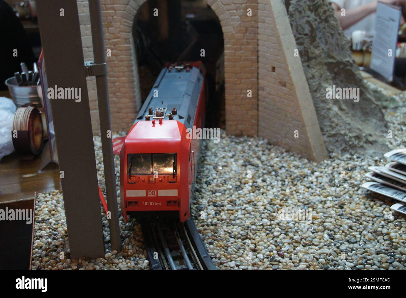 Model train emerging from tunnel. Red and blue locomotive with lights ...