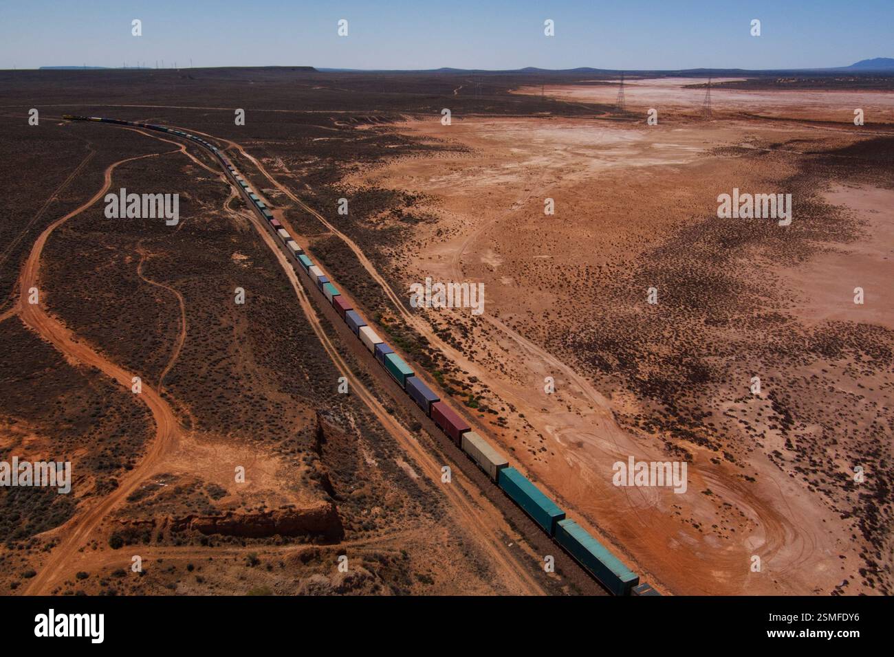 Aerial of shipping container intermodal freight train travelling through the Outback after ...