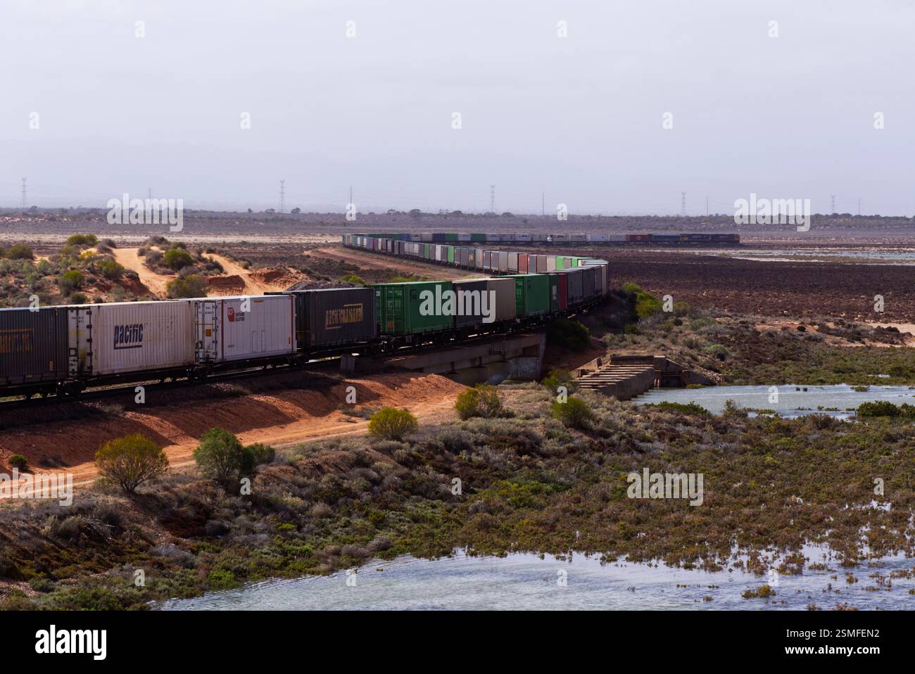 The image depicts a freight train traveling through the outback of Port ...