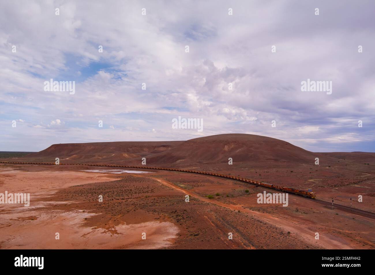 A train, carrying iron ore, is seen traveling through a vast, dry ...