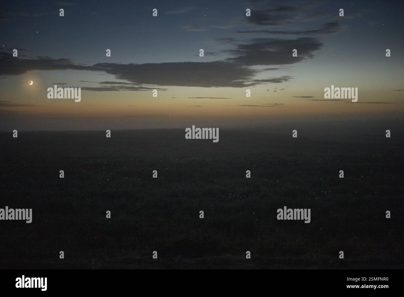 Dawn landscape with a crescent moon and clouds on the horizon in a calm ...
