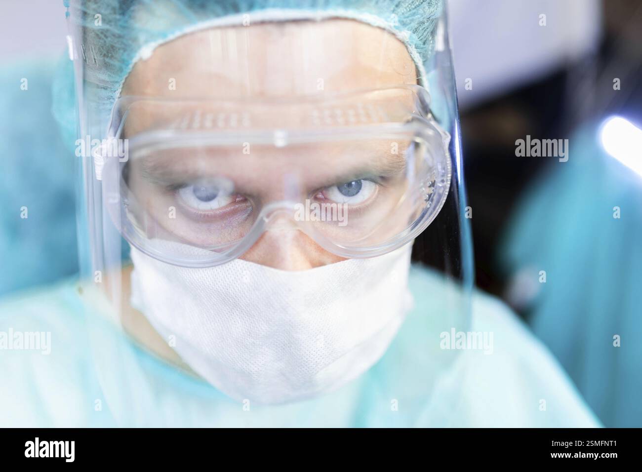 Medical personnel in aqua protective gear with an intense expression ...