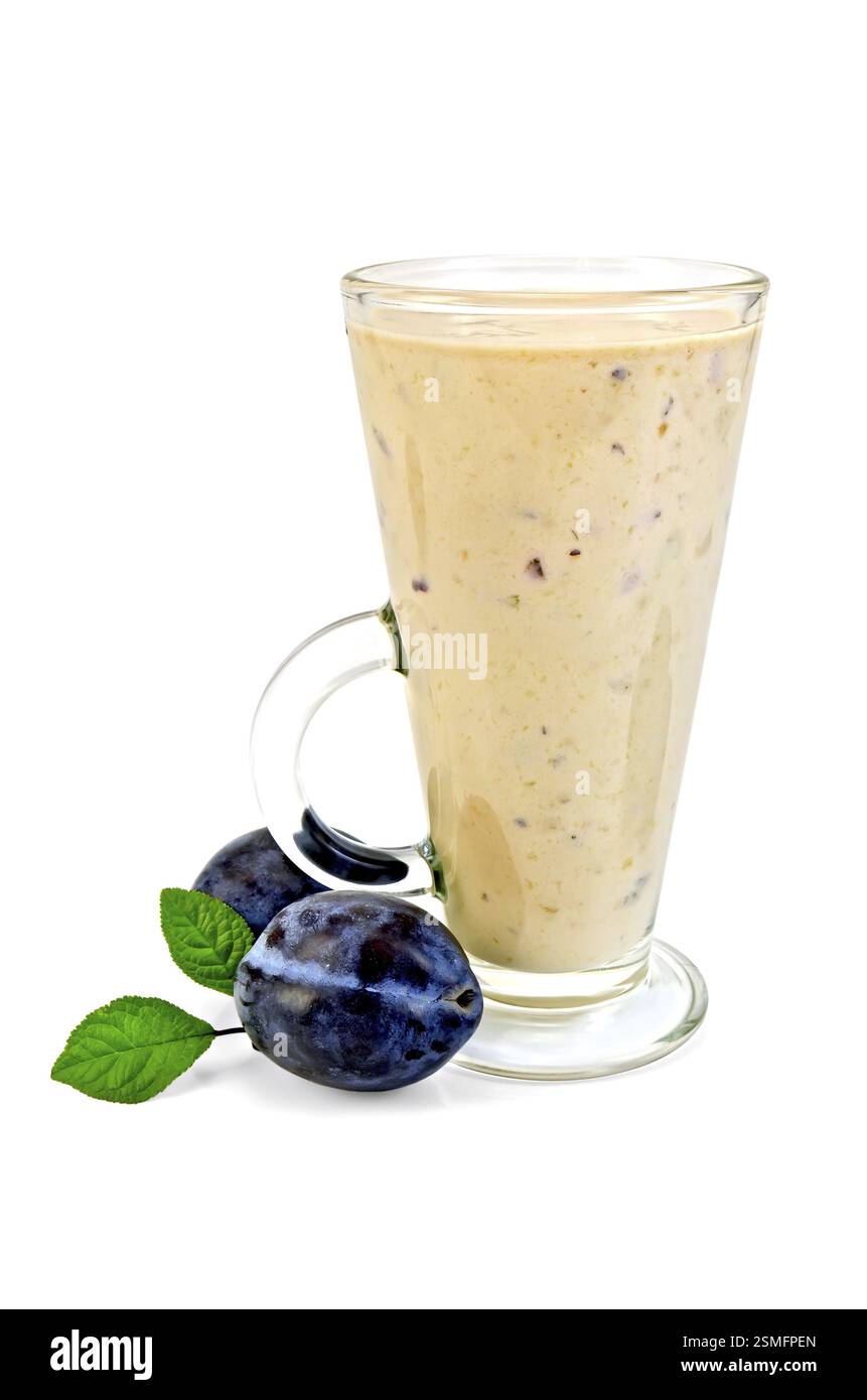 Milk shake in a glass beaker, two black plums with green leaves ...