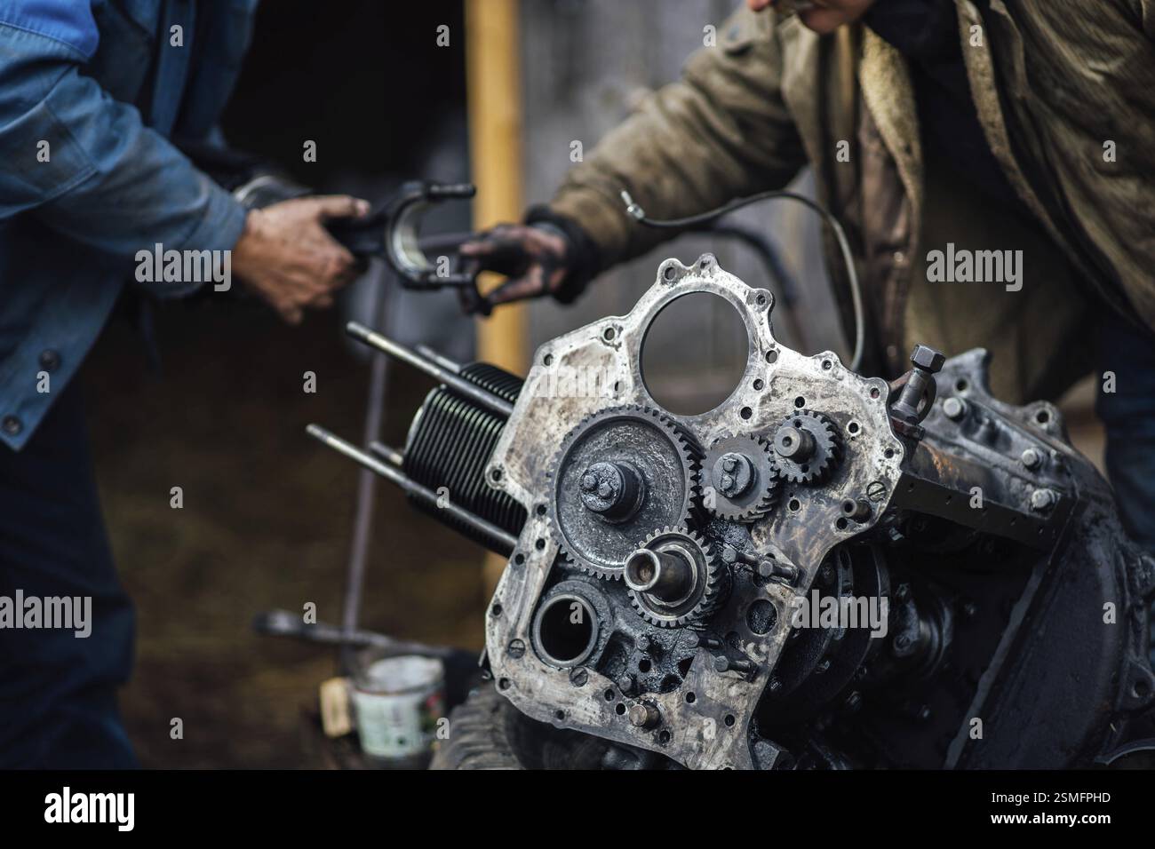 Two individuals working together on repairing an engine with visible ...