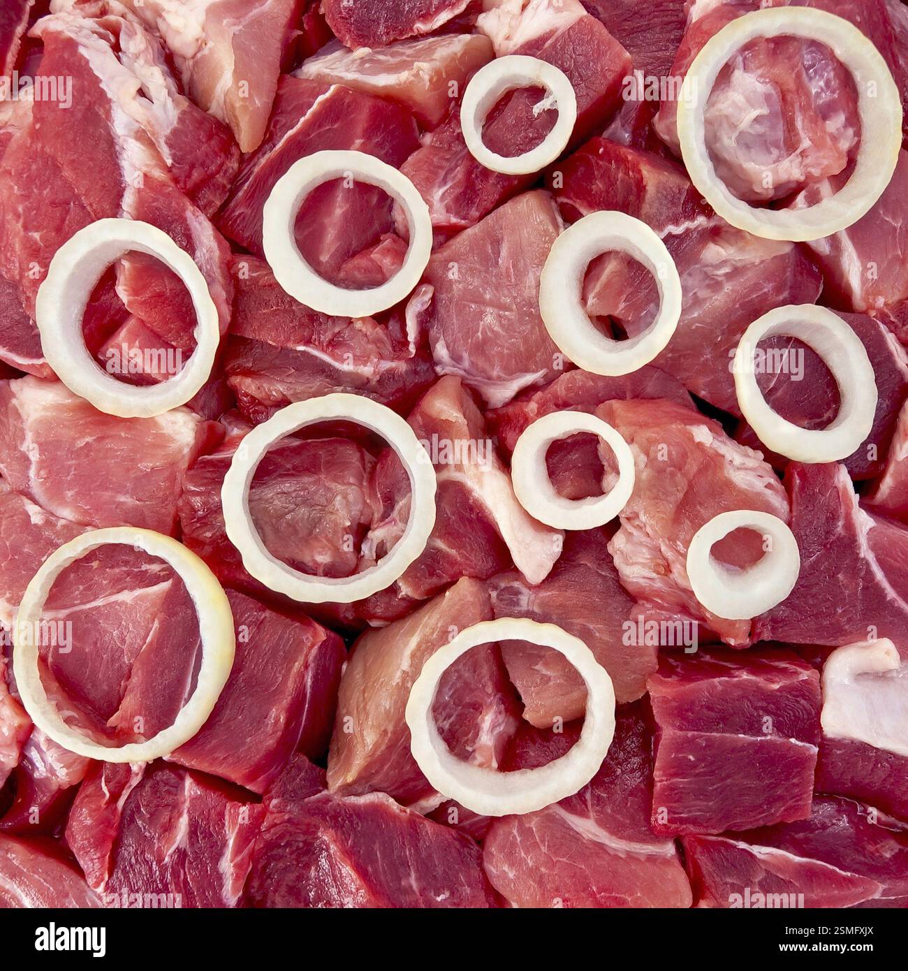 The rings of white onion on a background of red pieces of meat (texture ...