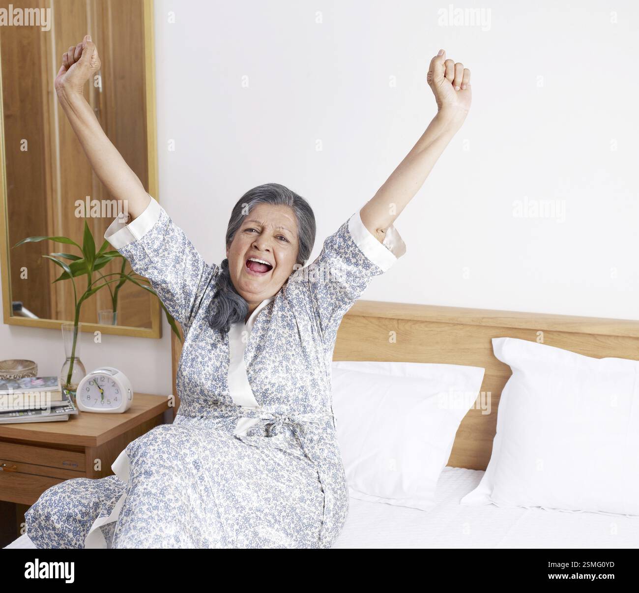 Old lady stretching both hands and yawning sitting on bed MR#702S Stock ...