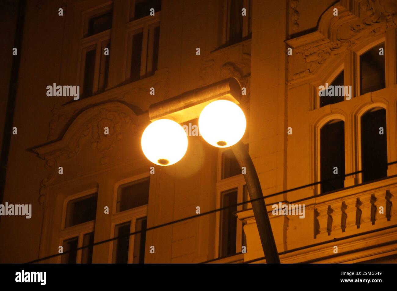 Street lamp illuminated orbs on vintage facade. Warm glow on urban ...