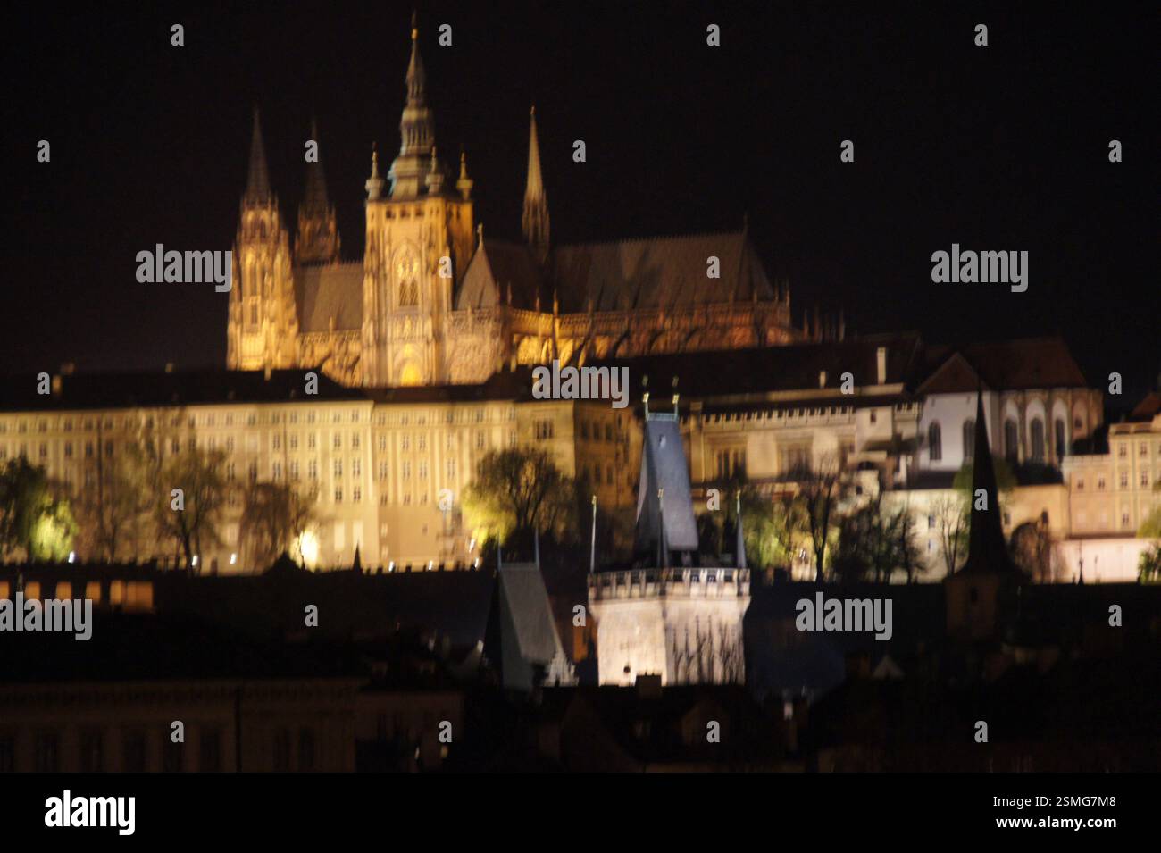 Prague Castle, a majestic complex illuminated at night, its spires and ...