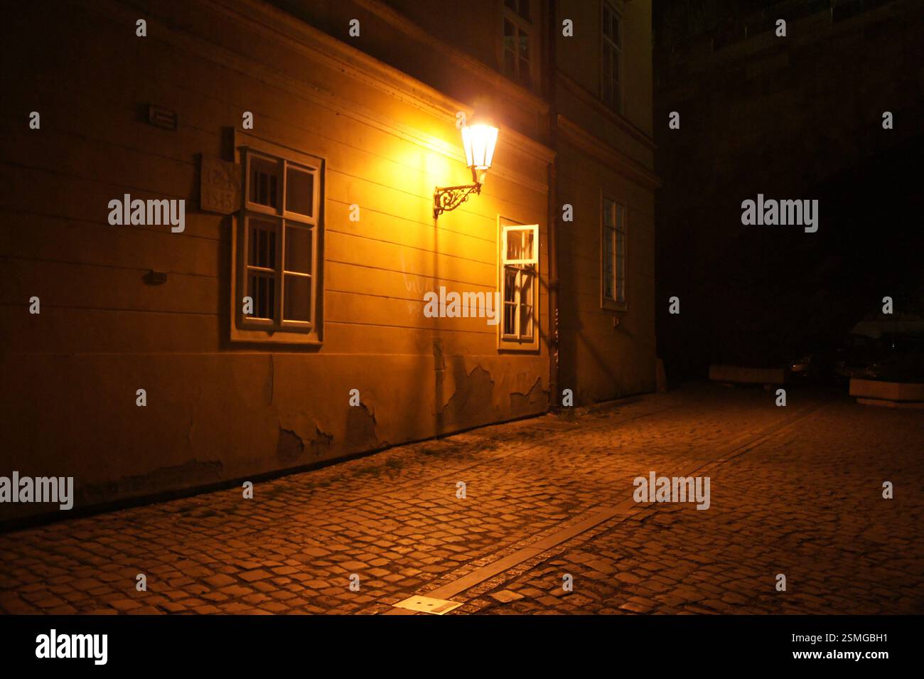 Old Town Prague cobblestone street illuminated by lamplight. Ancient ...