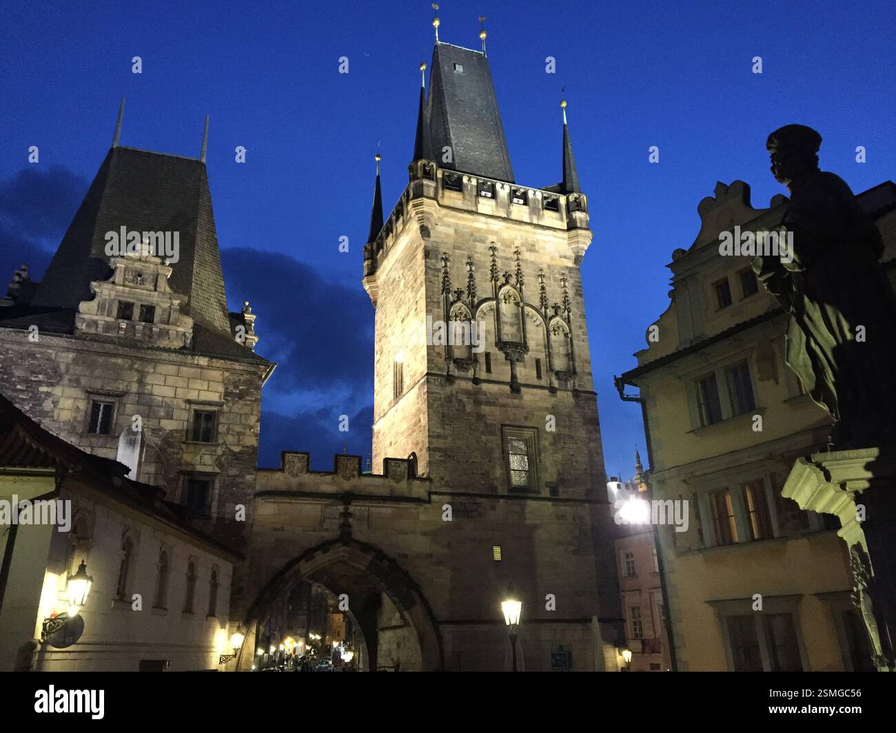 Charles Bridge, a Gothic masterpiece illuminated at dusk, stands as a ...