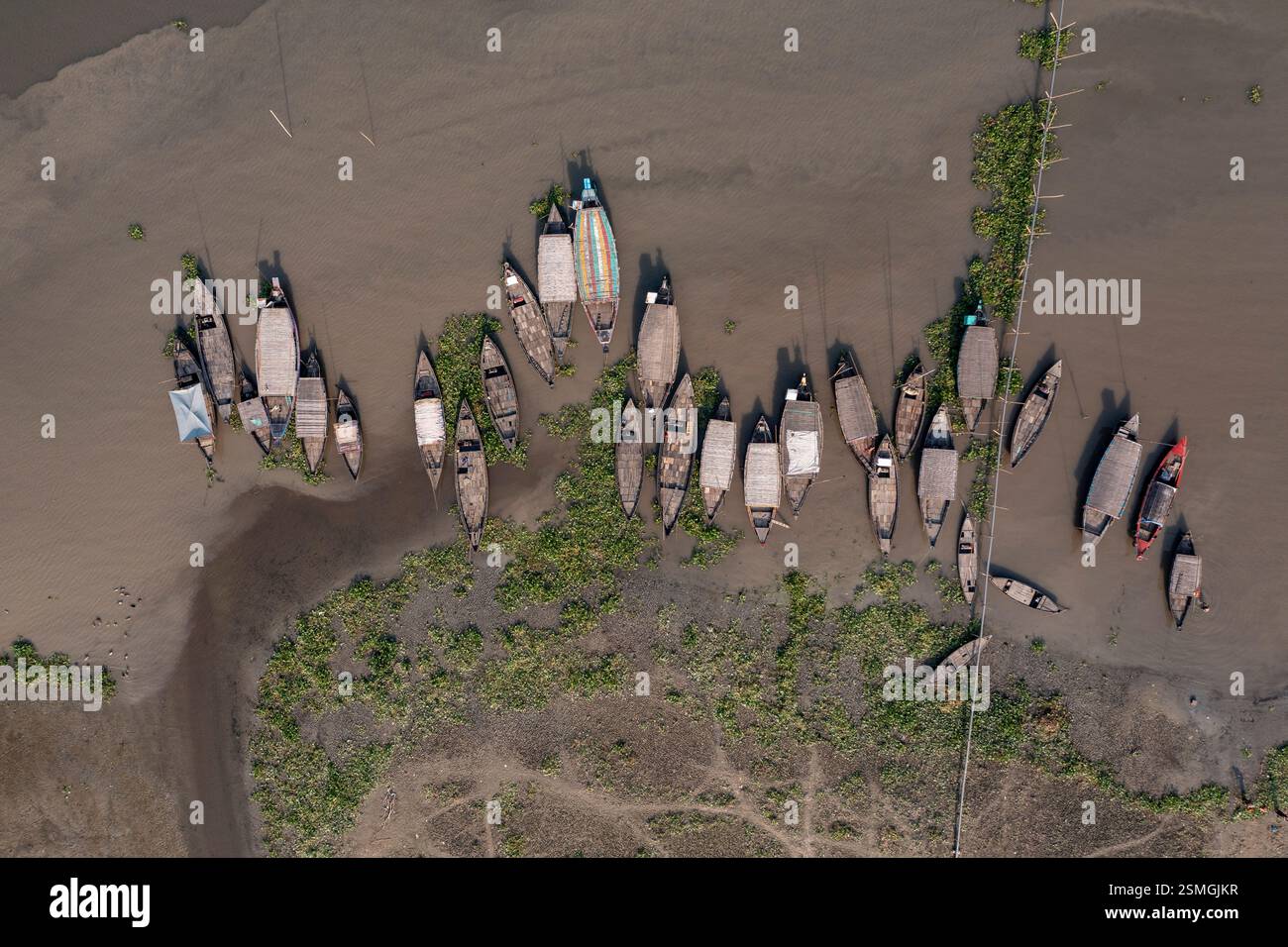 A cluster of fishing boats rests along the banks of the Meghna River in ...