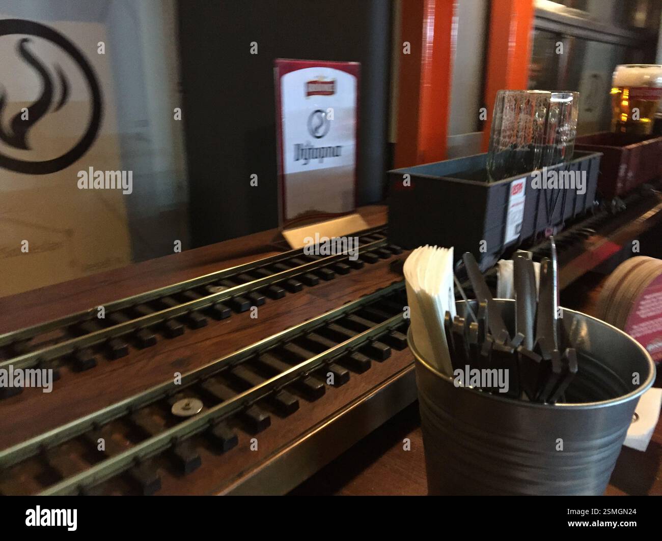 Restaurant counter with train tracks running along it. Beer glasses and ...