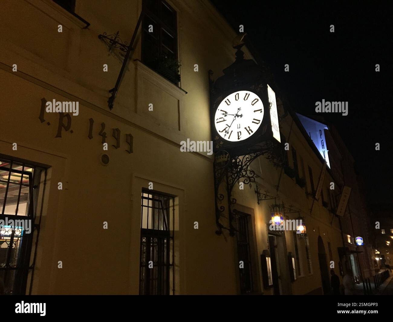 Clock on building facade. Illuminated, ornate clock face with Roman ...