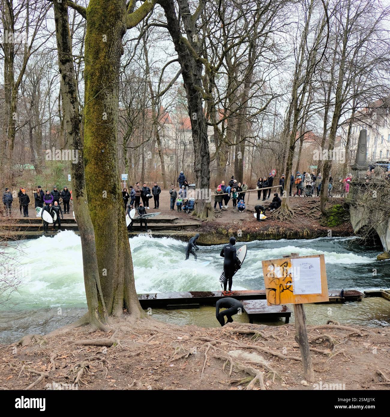 Surfers riding waves at the Eisbach River in the English Garden grounds ...