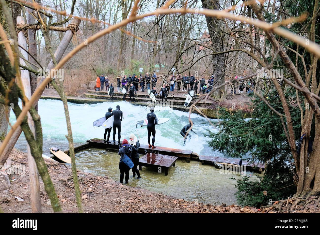 Surfers riding waves at the Eisbach River in the English Garden grounds ...