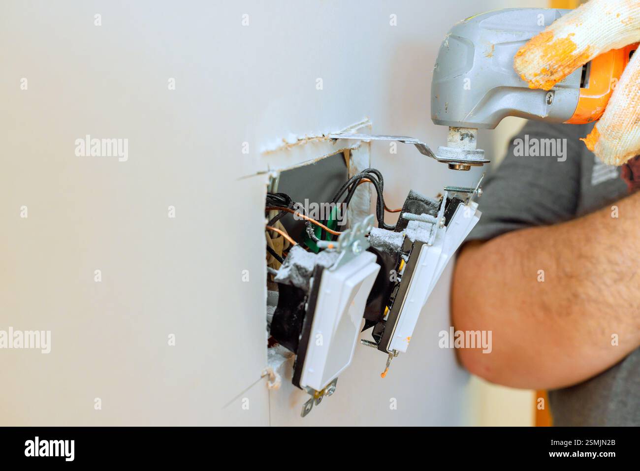An electrician is repairing wall socket, using multi tools for ...