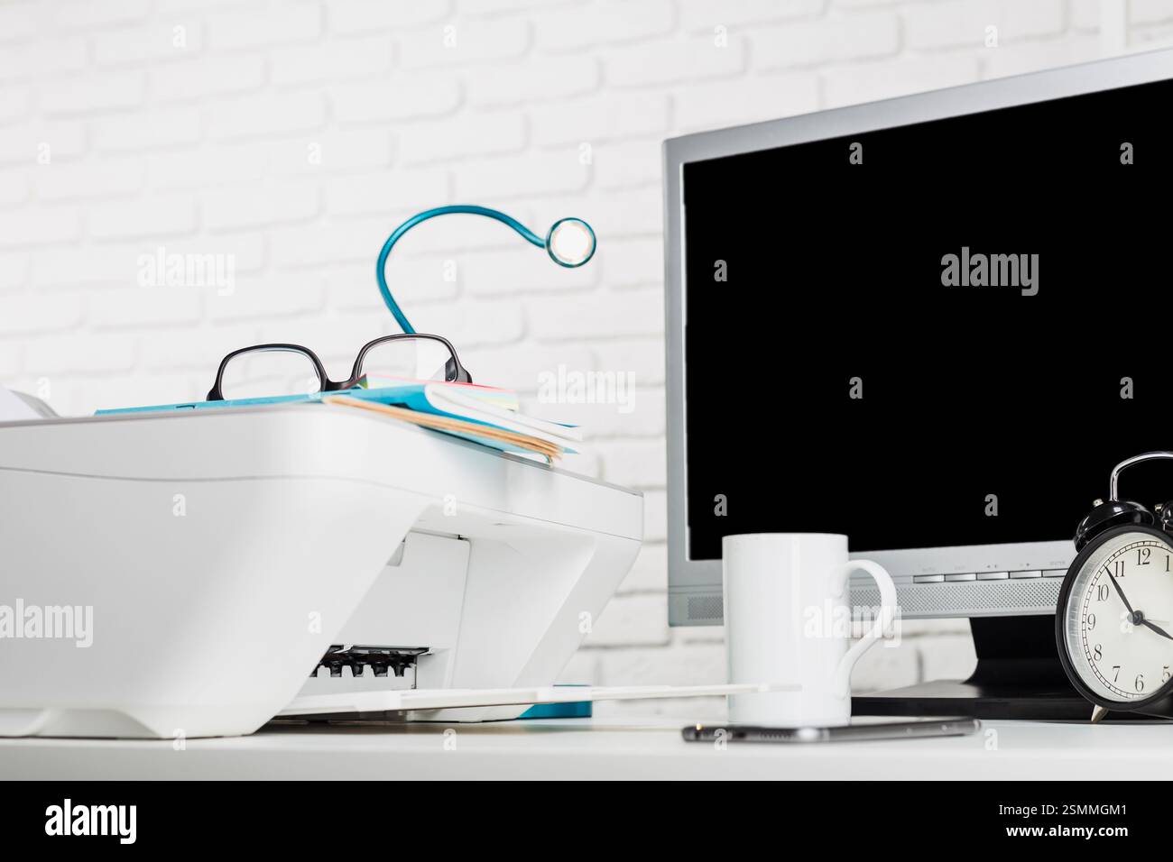 Home office workspace featuring printer, monitor, clock, and coffee cup ...