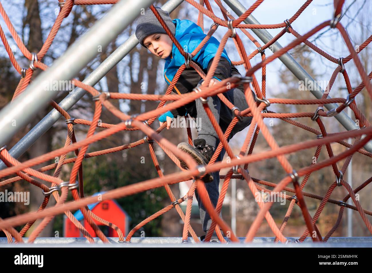 A child climbs up an alpine grid in a park on a playground on spring ...