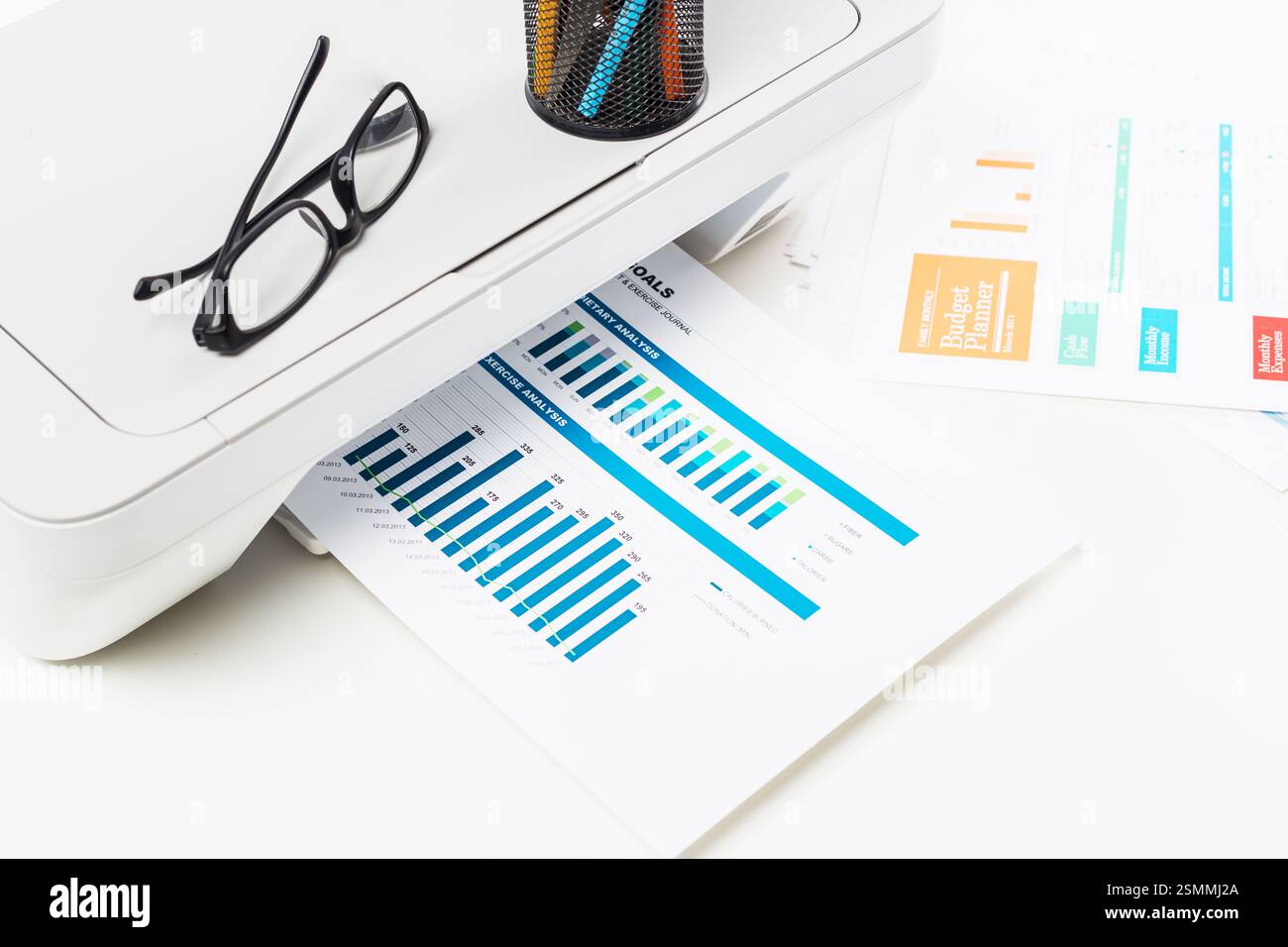 Office workspace featuring a printer, printed report, glasses, and ...